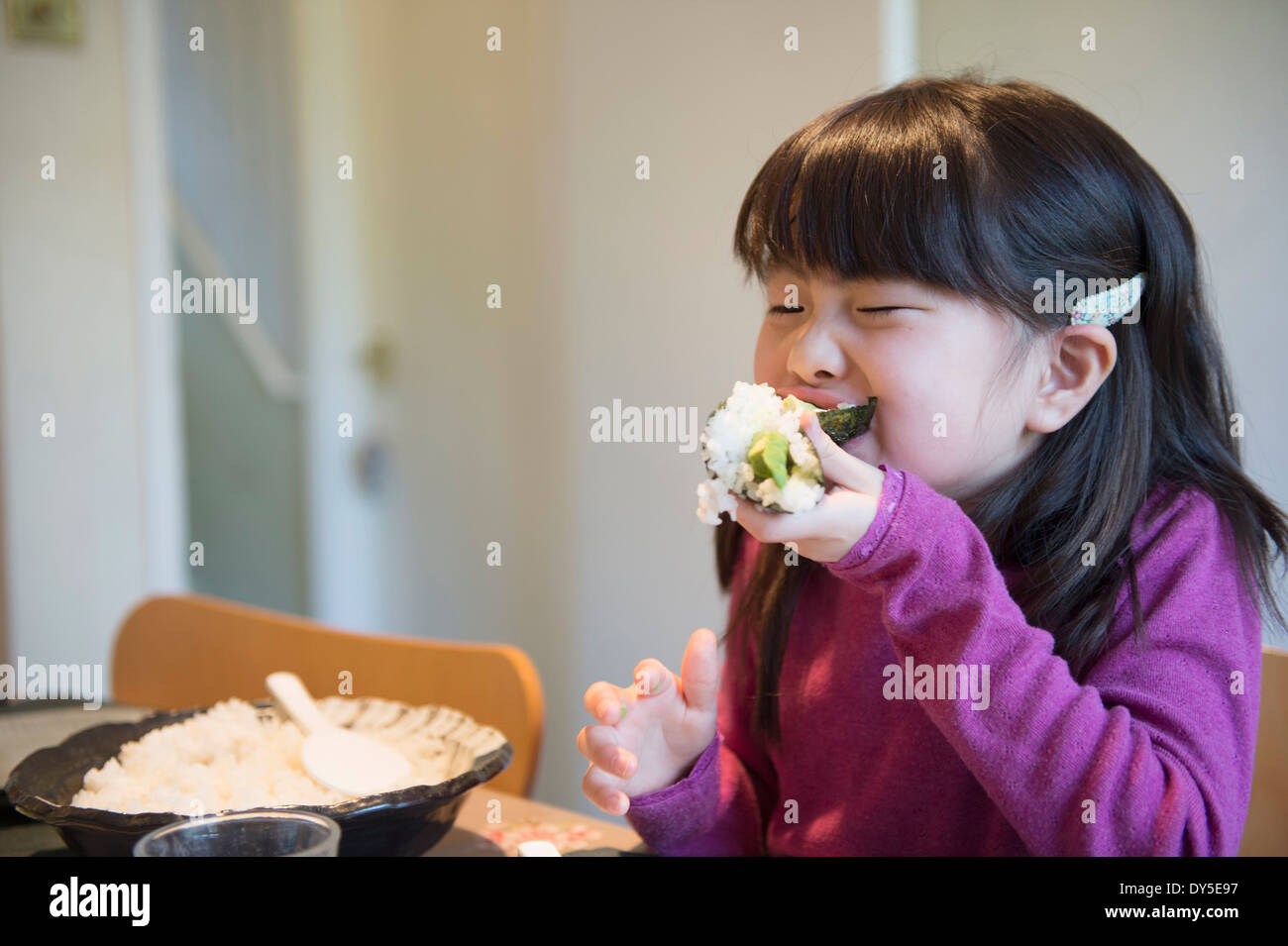 Girl eating large rice parcel at dining table Stock Photo - Alamy