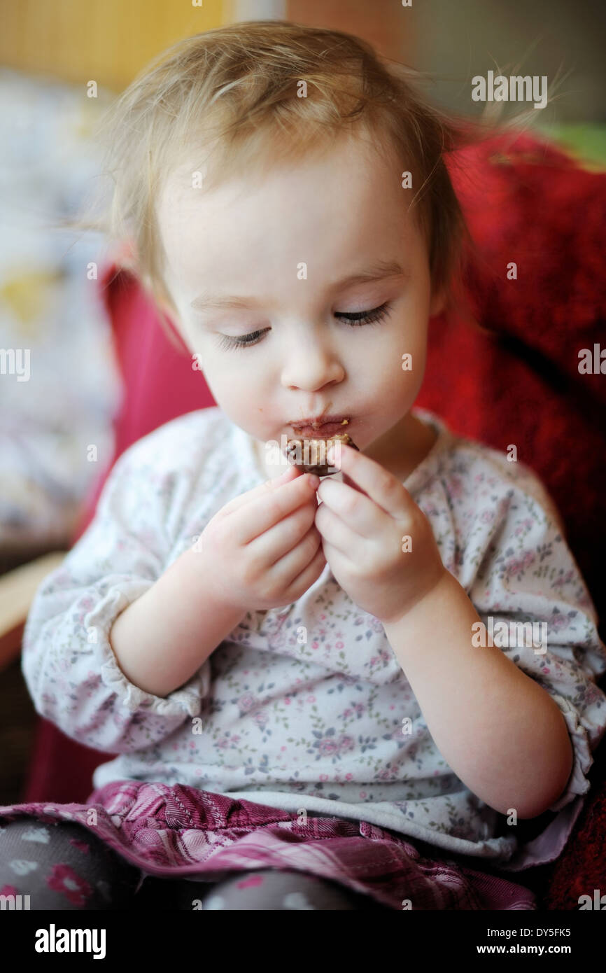 Little toddler girl eating chocolate candy Stock Photo - Alamy