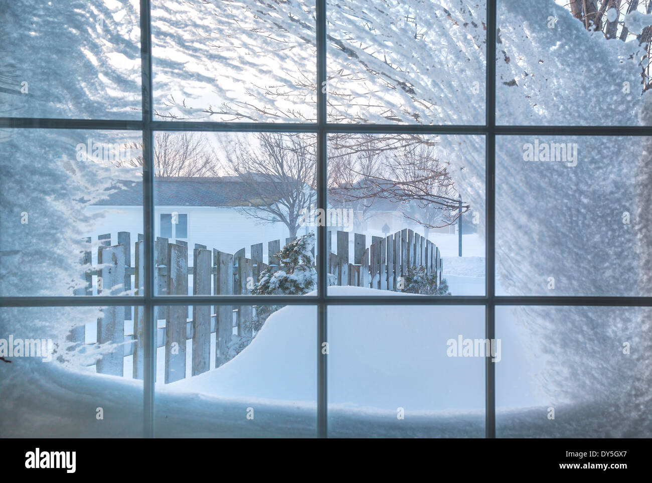 Snow covered window with a view out into a residential neighborhood ...