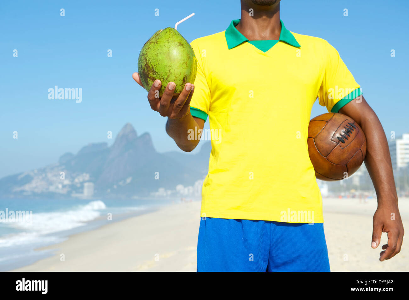 Brazilian soccer player in Brazil colors holding vintage brown football ...