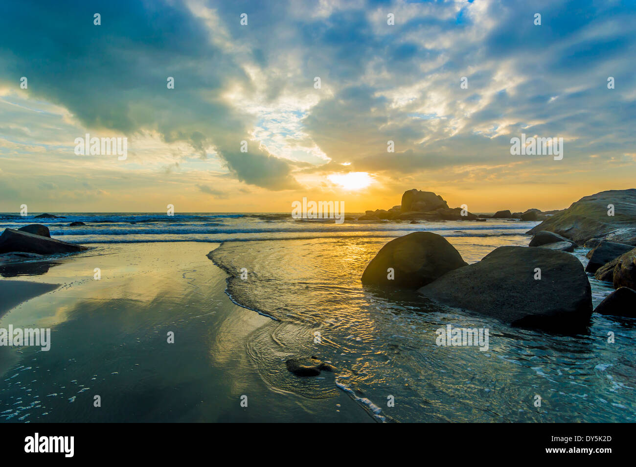 Colorful cloudy sunrise at the beach with reflection and rocks Stock ...