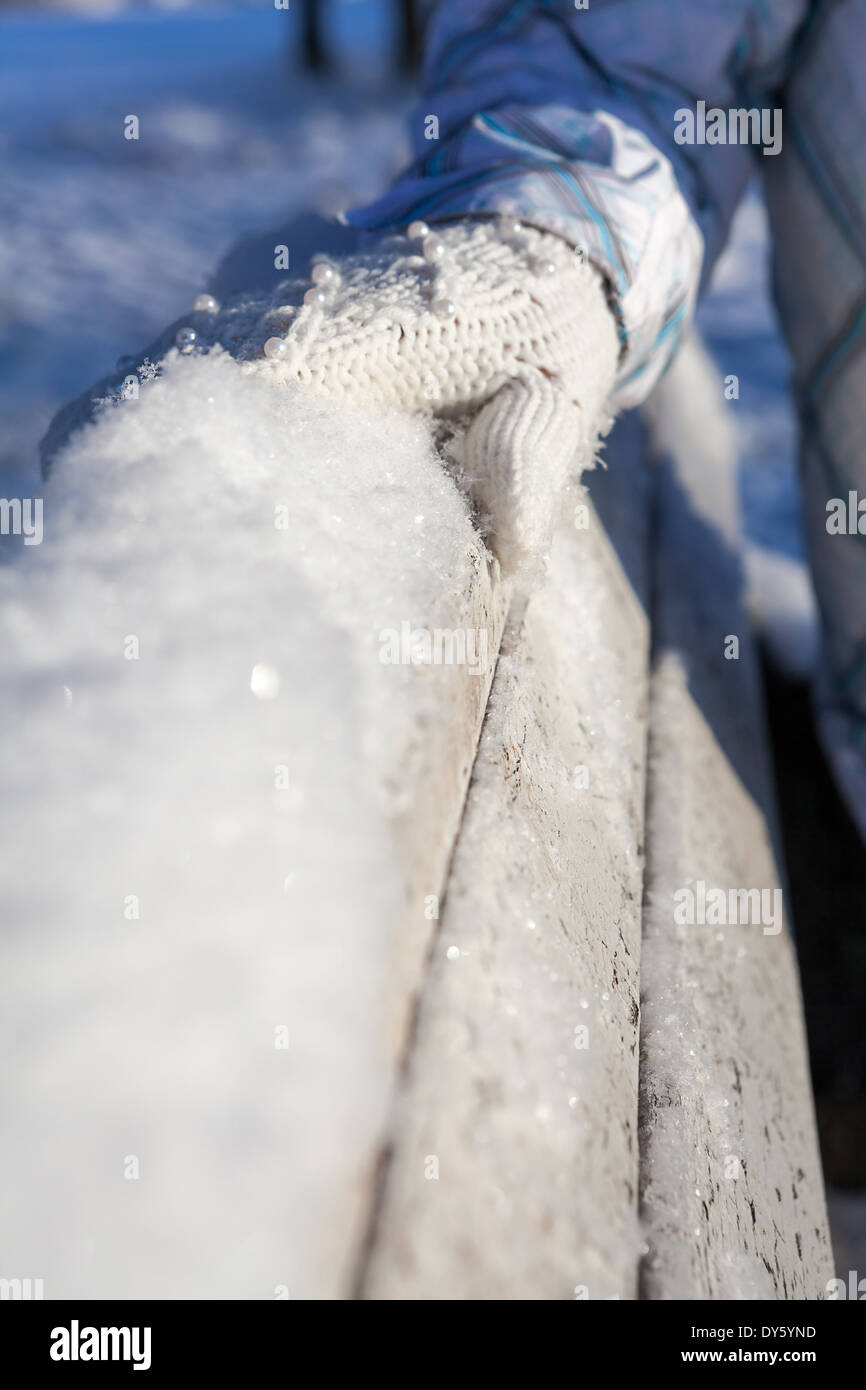 White knitted mitten laying on back of the bench in snow Stock Photo ...