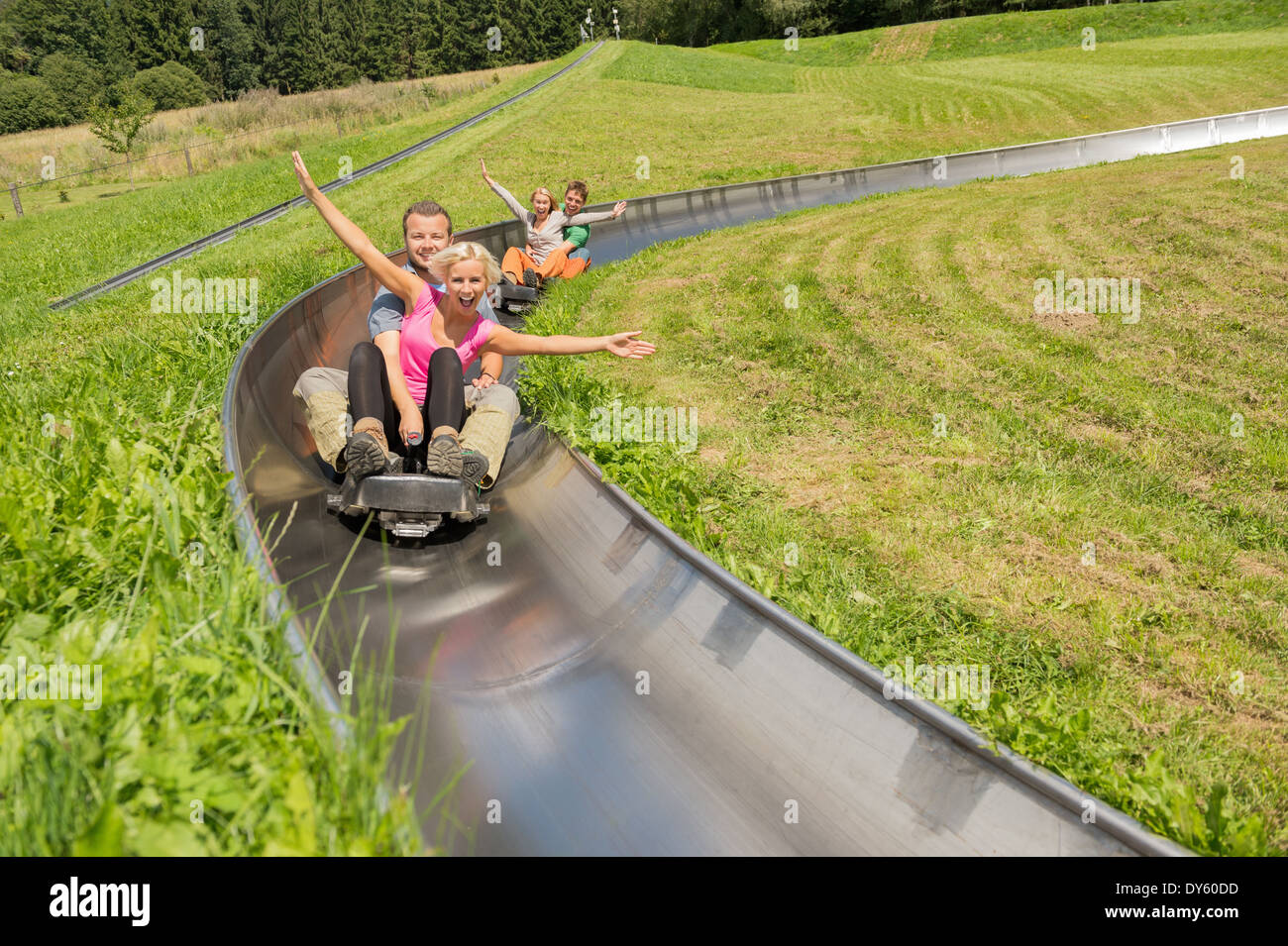 Excited young couples enjoying alpine coaster luge during summer Stock ...