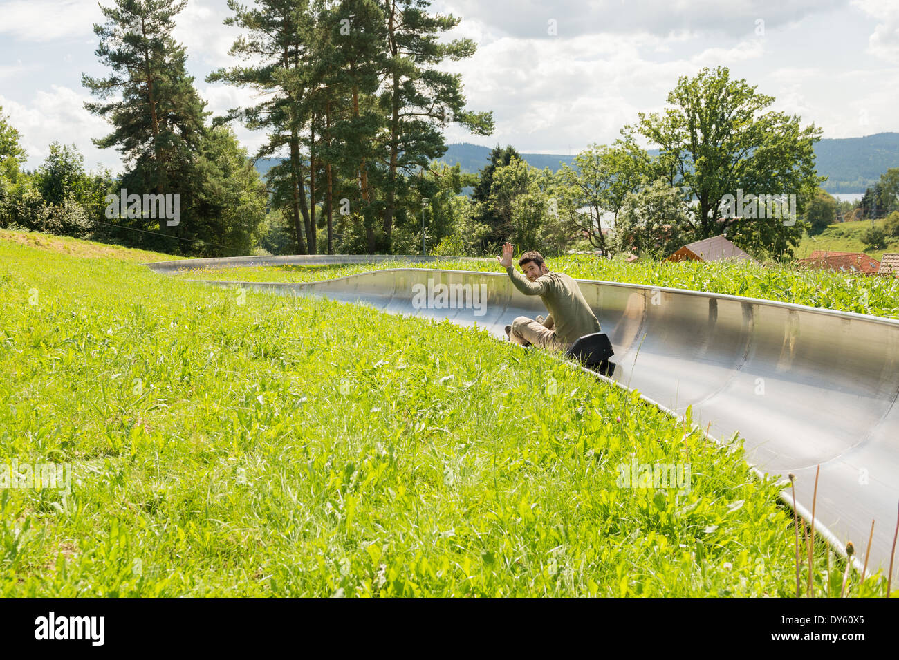Young man enjoying summer sledge ride Stock Photo - Alamy