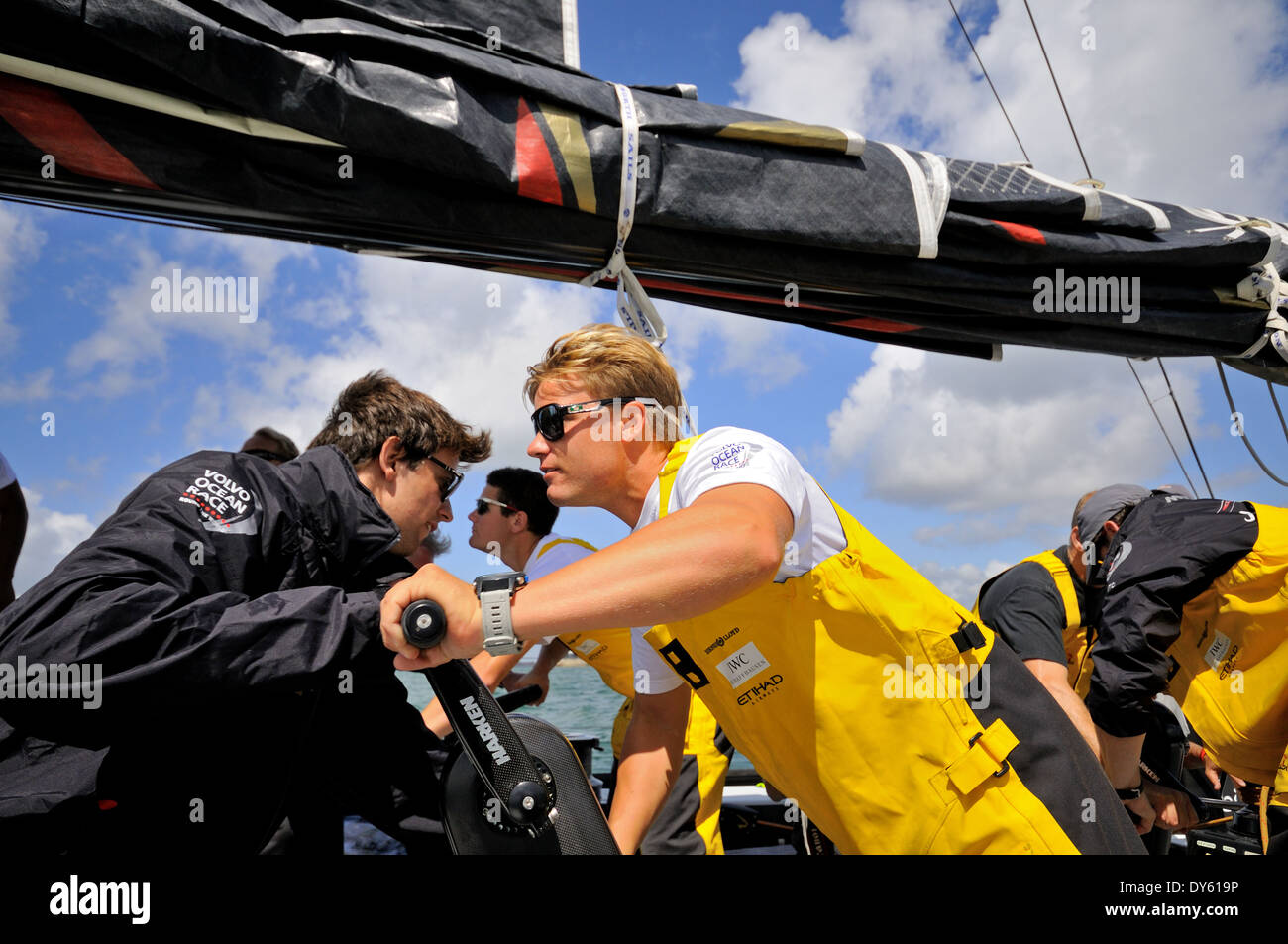 Crewmen in full weather gear winch grinding aboard ocean racing yacht ...