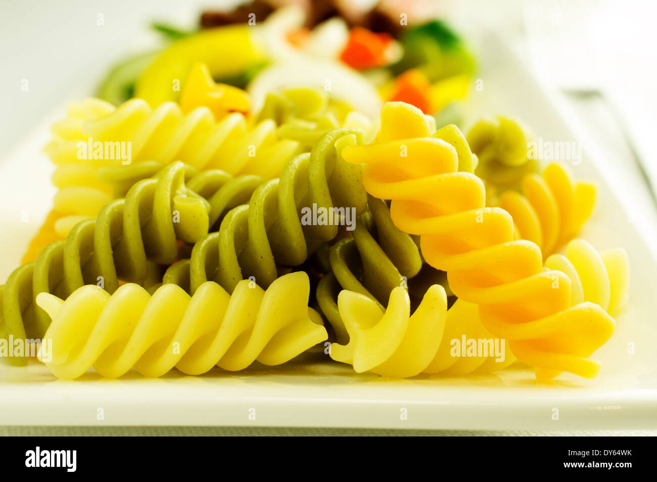 Colorful pasta spirals (red, green, yellow) on porcelain rectangular ...