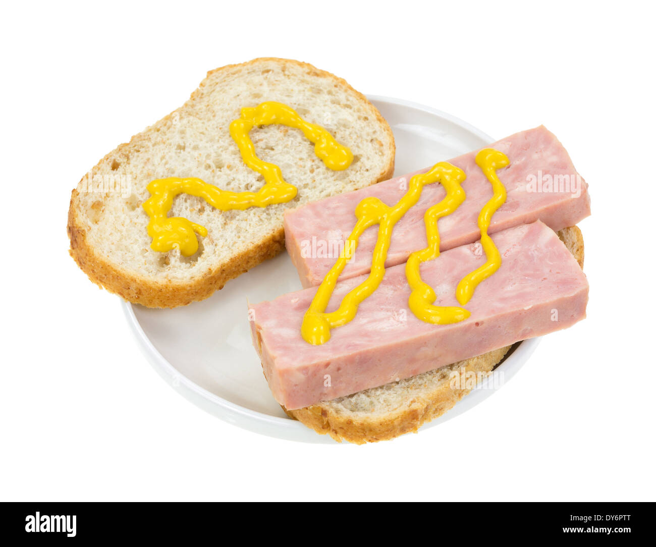 Two slices of canned ham on Italian bread with mustard on a small plate ...