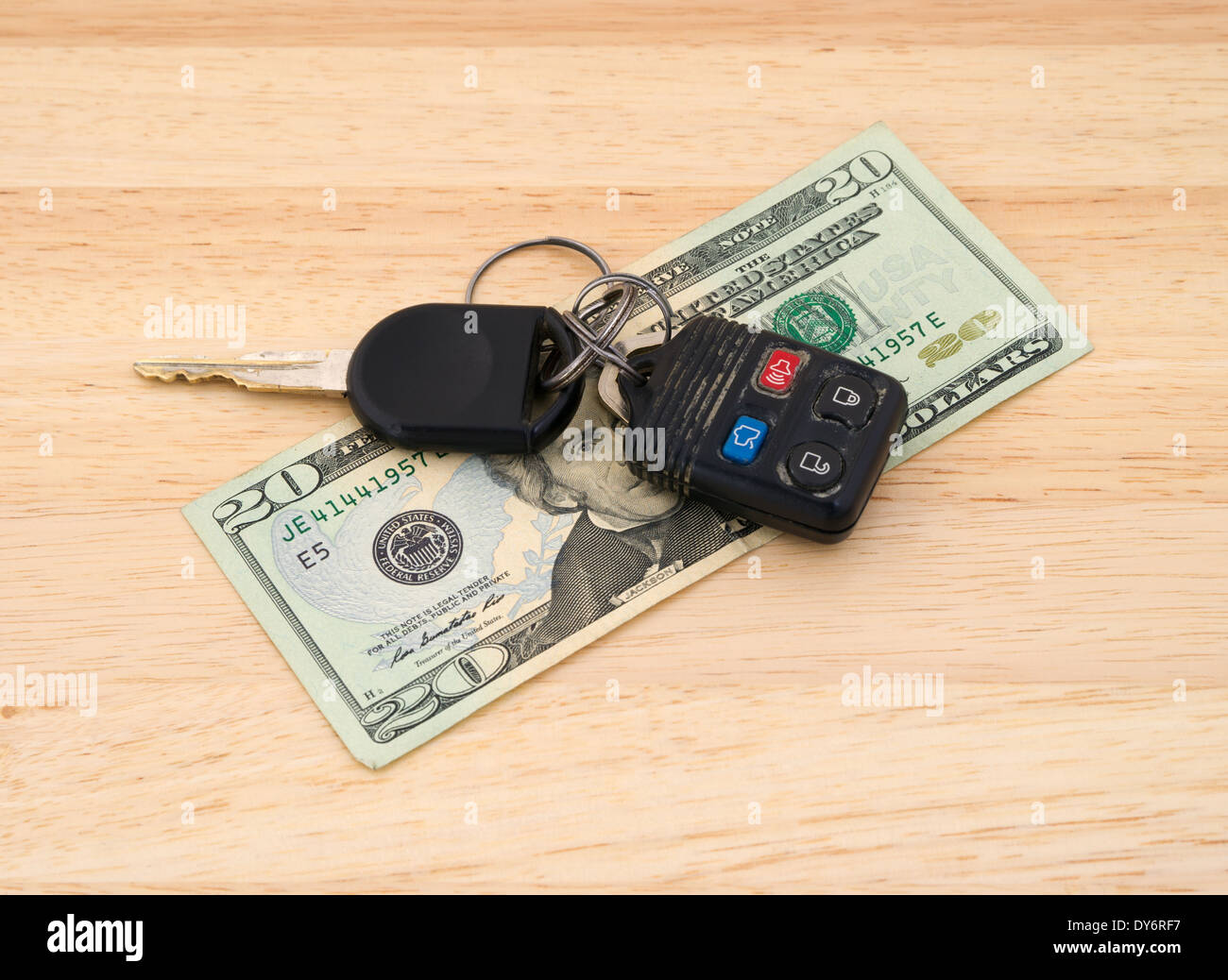 A set of used car keys atop a twenty dollar bill signifying gas money ...