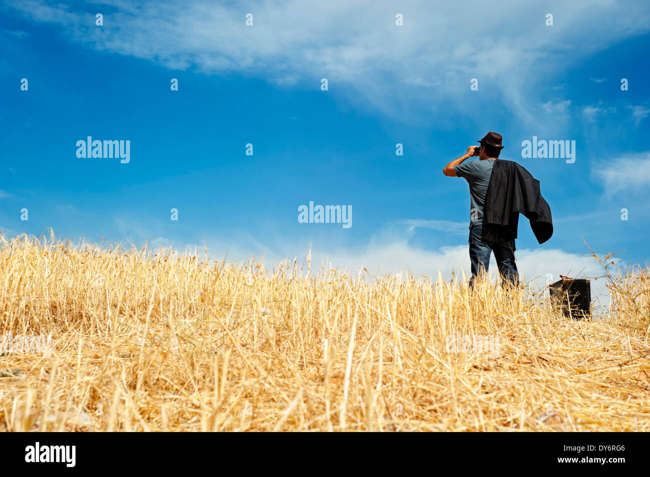Man standing in a field watching with binoculars Stock Photo - Alamy