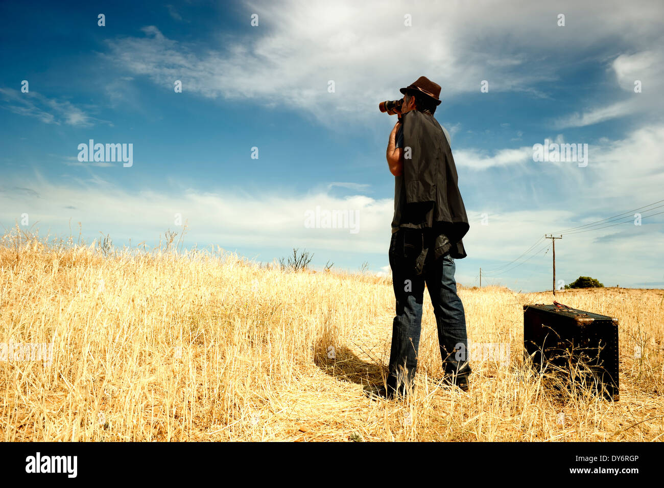 Man standing in a field watching with binoculars Stock Photo - Alamy