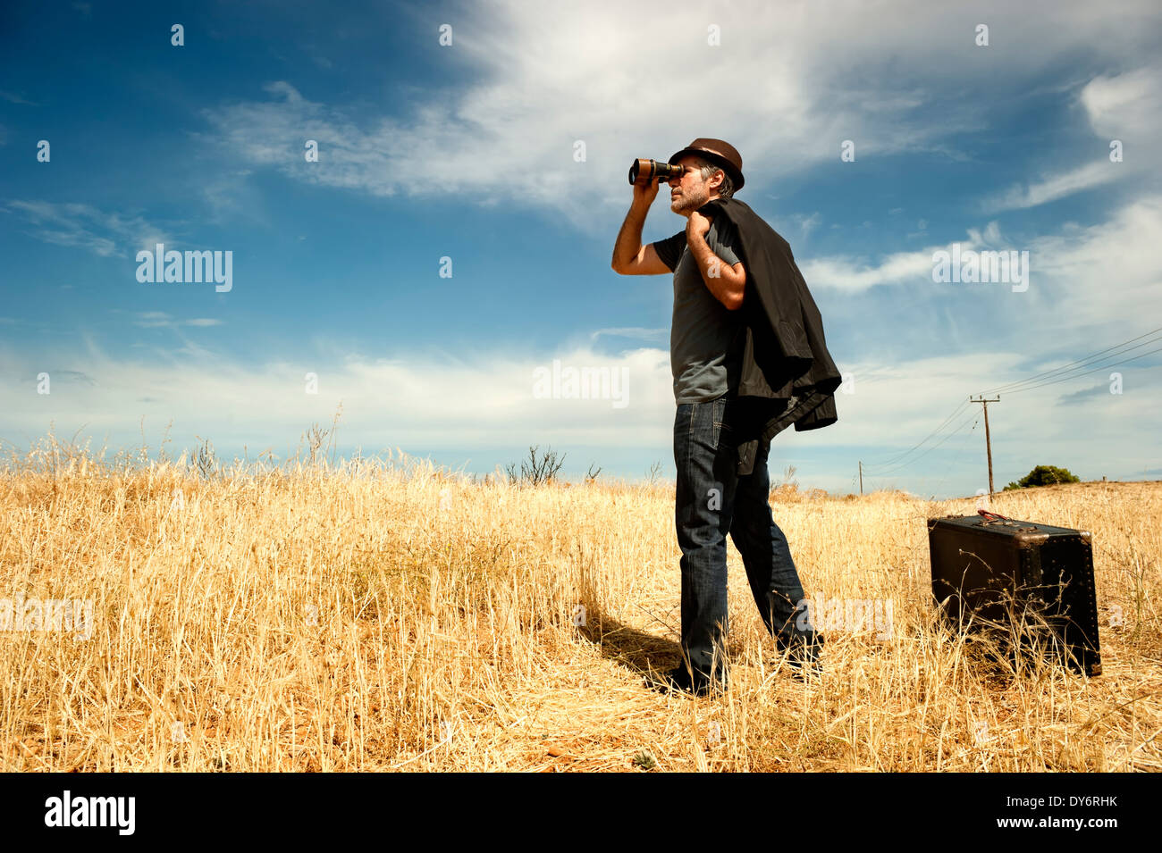 Man standing in a field watching with binoculars Stock Photo - Alamy