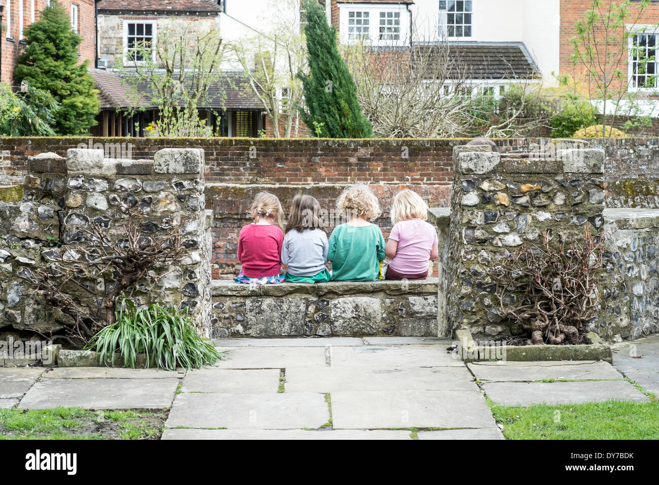 Four little girls sat on wall with their backs to camera Stock Photo ...