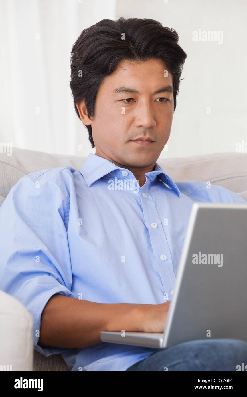 Serious man sitting on couch using laptop Stock Photo - Alamy