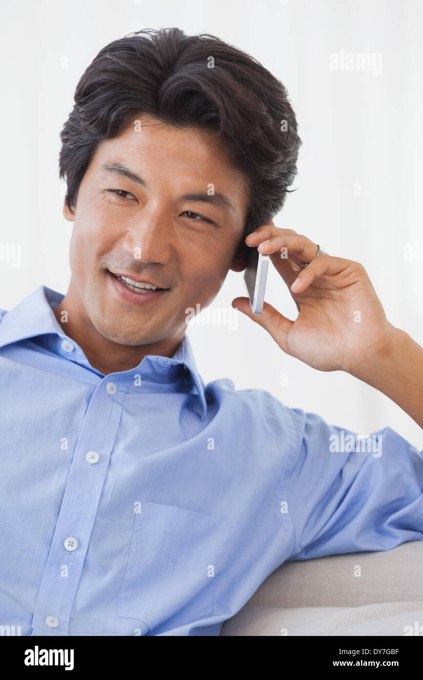Happy man sitting on couch on the phone Stock Photo - Alamy