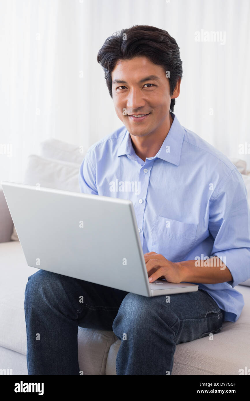 Happy man sitting on couch using laptop Stock Photo - Alamy