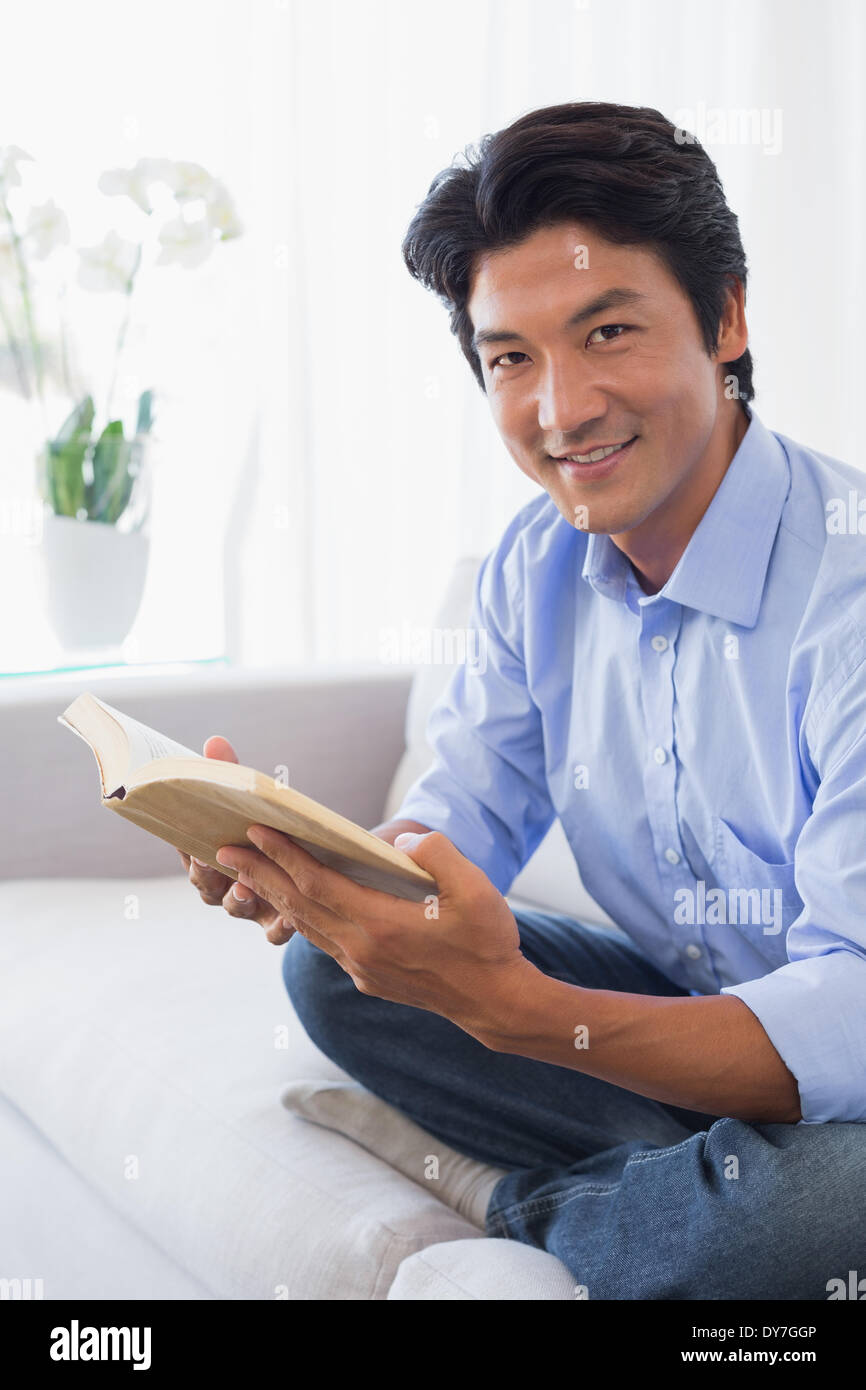 Happy man sitting on couch reading Stock Photo - Alamy
