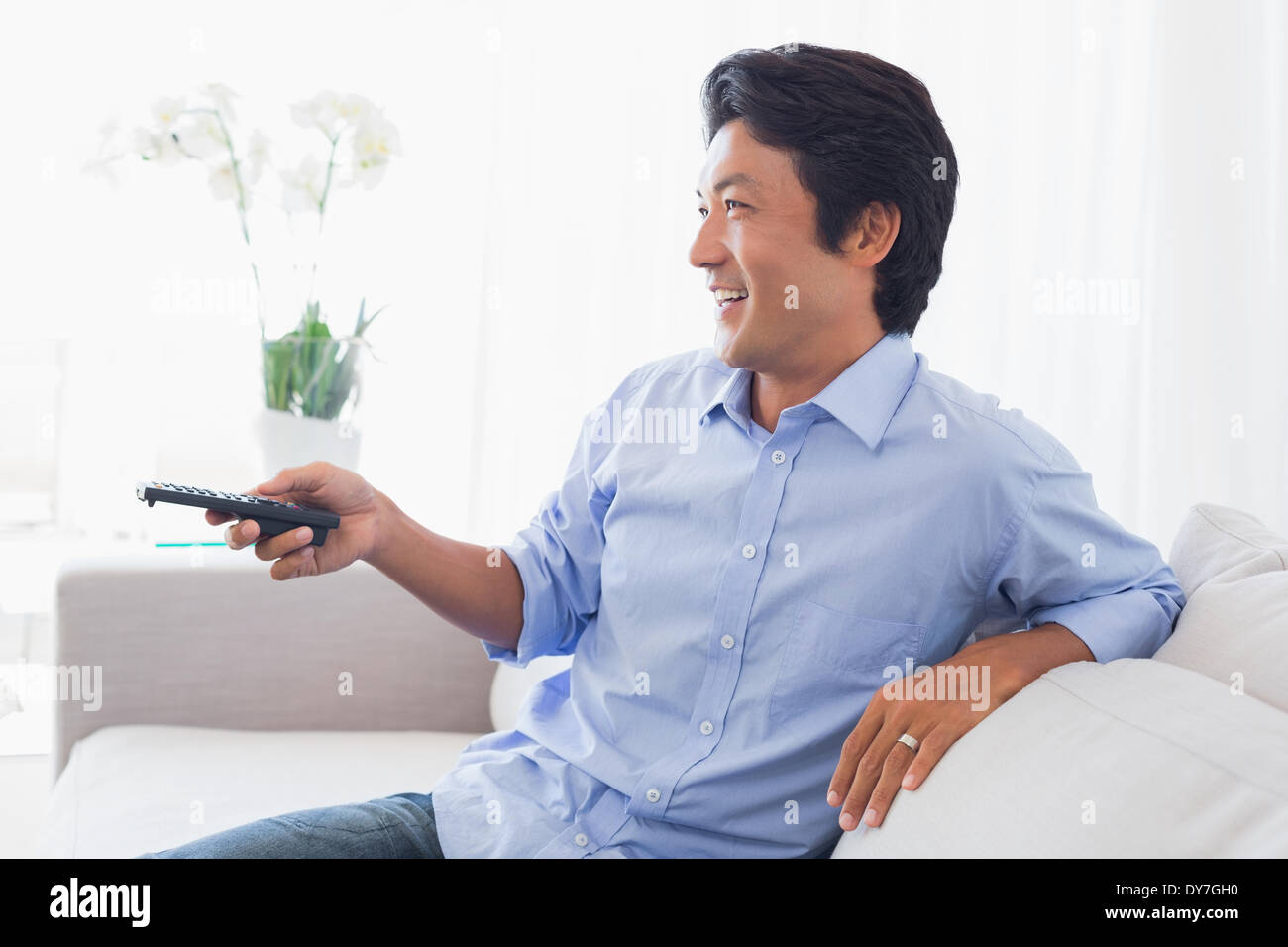 Happy man relaxing on couch watching tv Stock Photo - Alamy