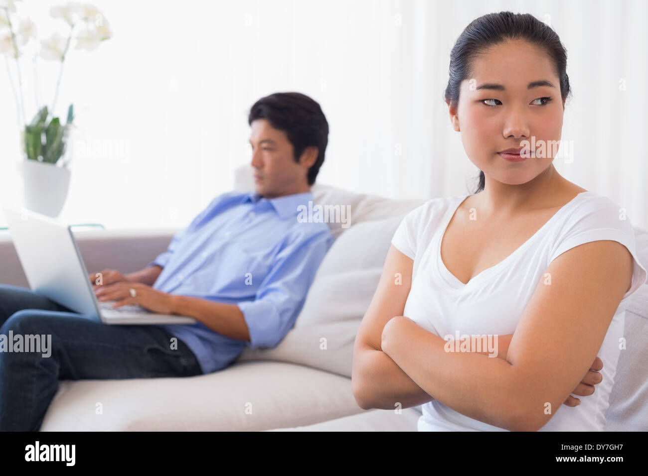Upset woman sitting on couch while boyfriend uses laptop Stock Photo ...