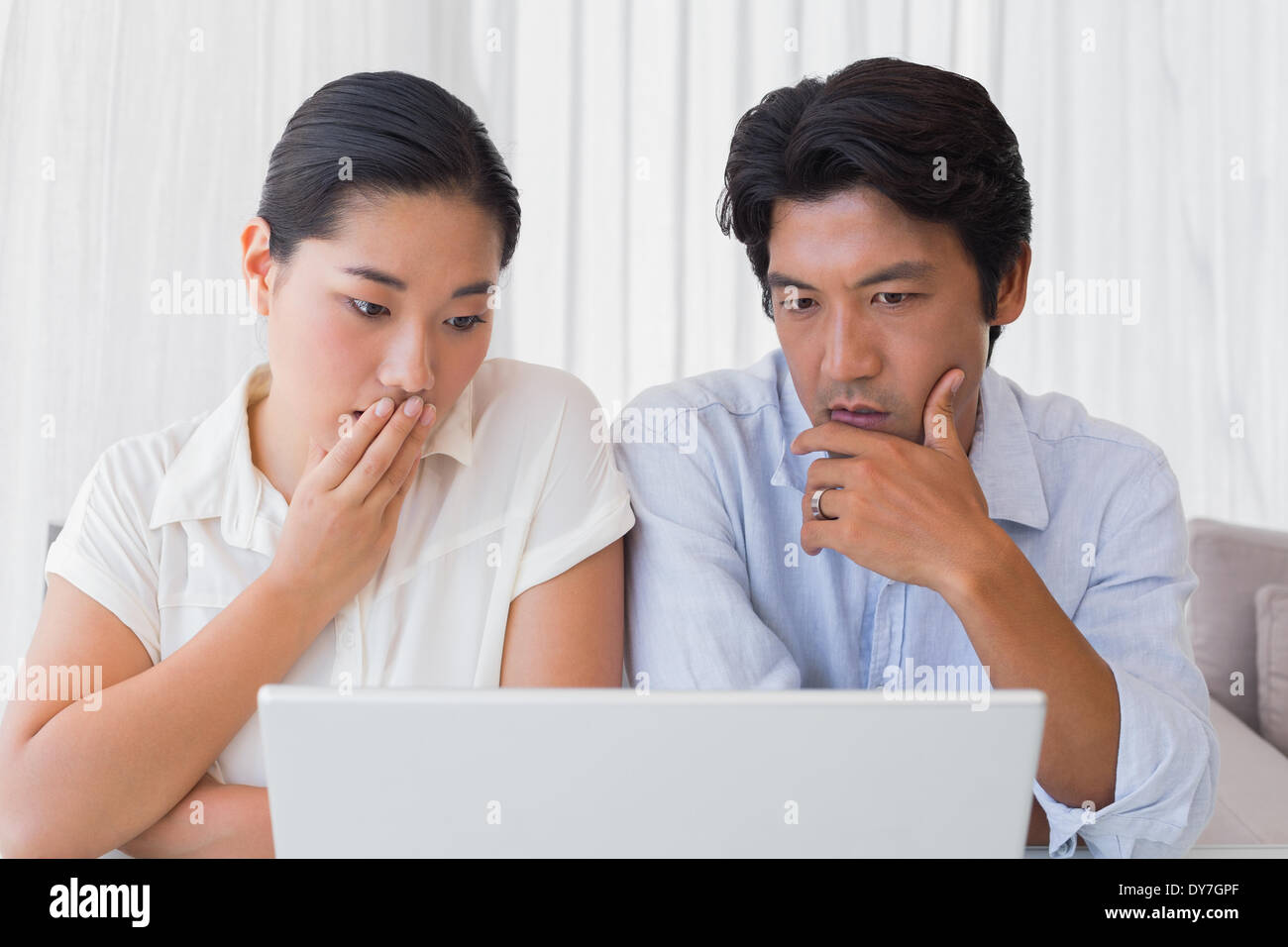 Worried couple using laptop together Stock Photo - Alamy
