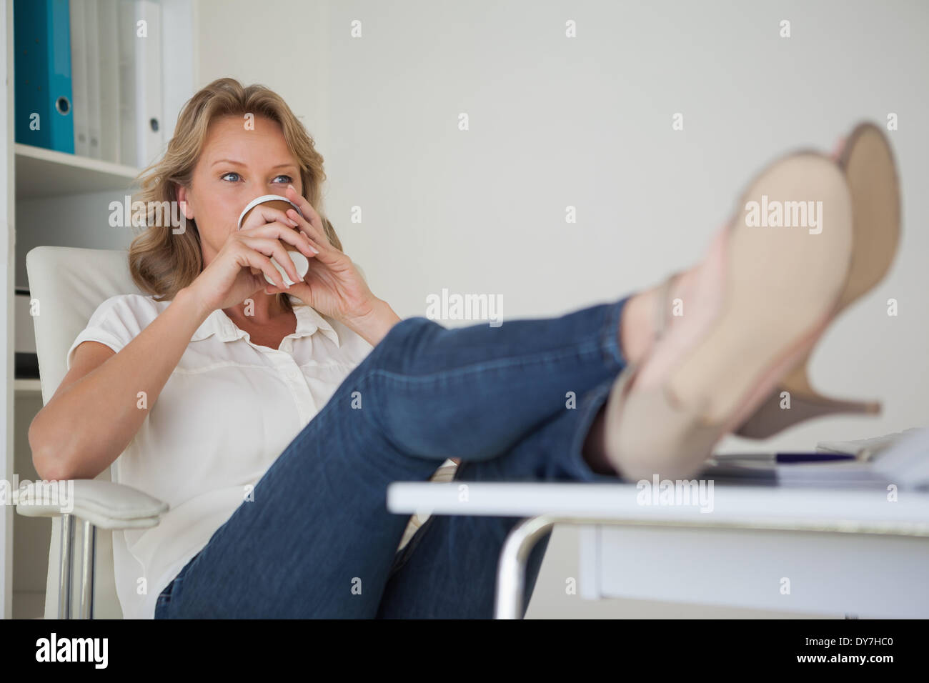 Casual businesswoman having a coffee with her feet up at desk Stock ...