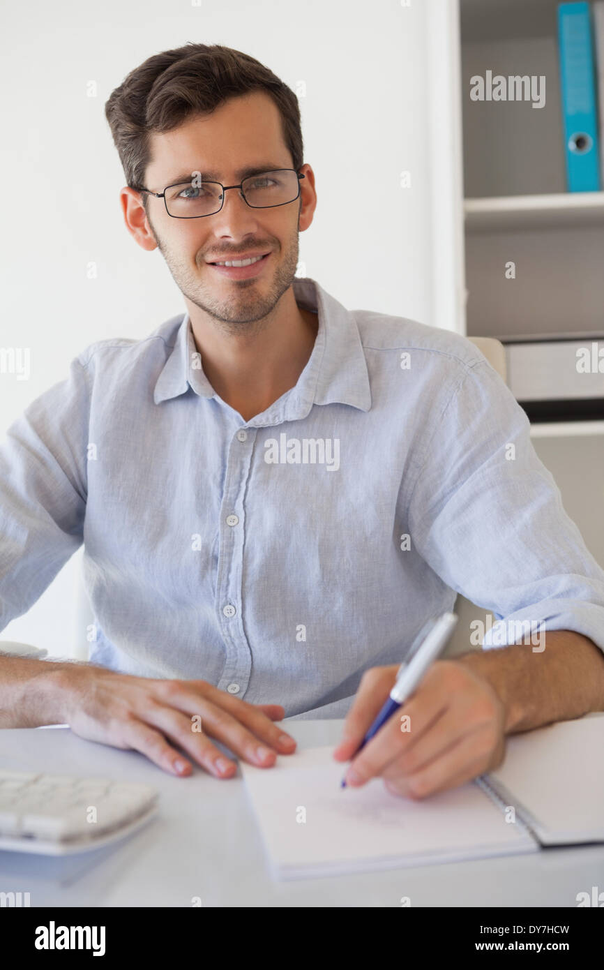 Casual smiling businessman taking notes at his desk Stock Photo - Alamy