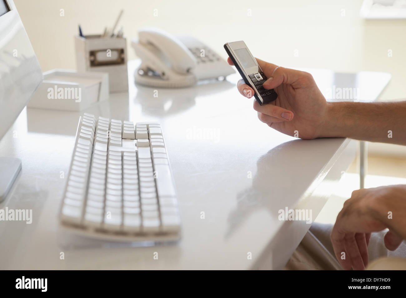 Casual businessman sending a text at his desk in the office Stock Photo ...