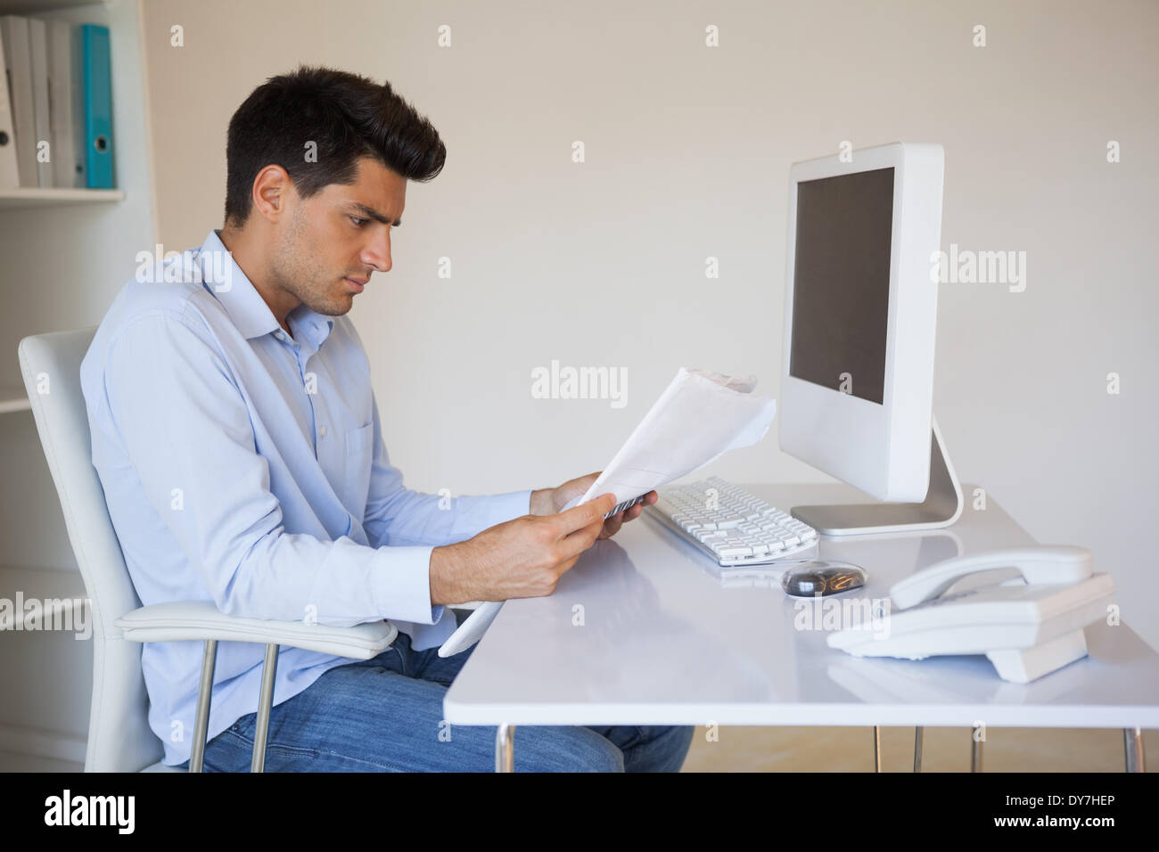 Casual businessman reading document at his desk Stock Photo - Alamy