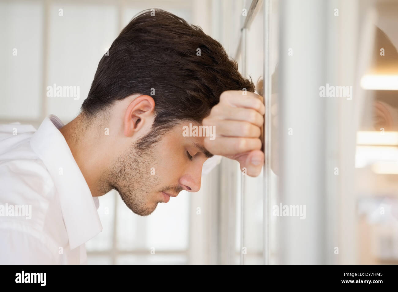 Upset man leaning his head against a wall Stock Photo - Alamy