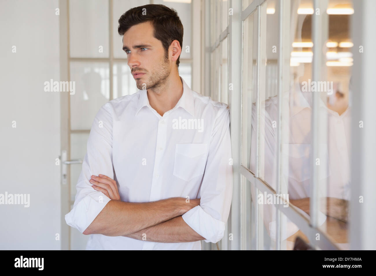 Casual upset businessman leaning against window Stock Photo - Alamy