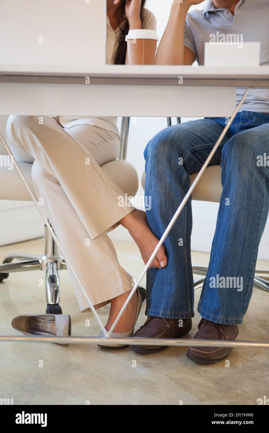 Casual businesswoman playing footsie with colleague under desk Stock ...
