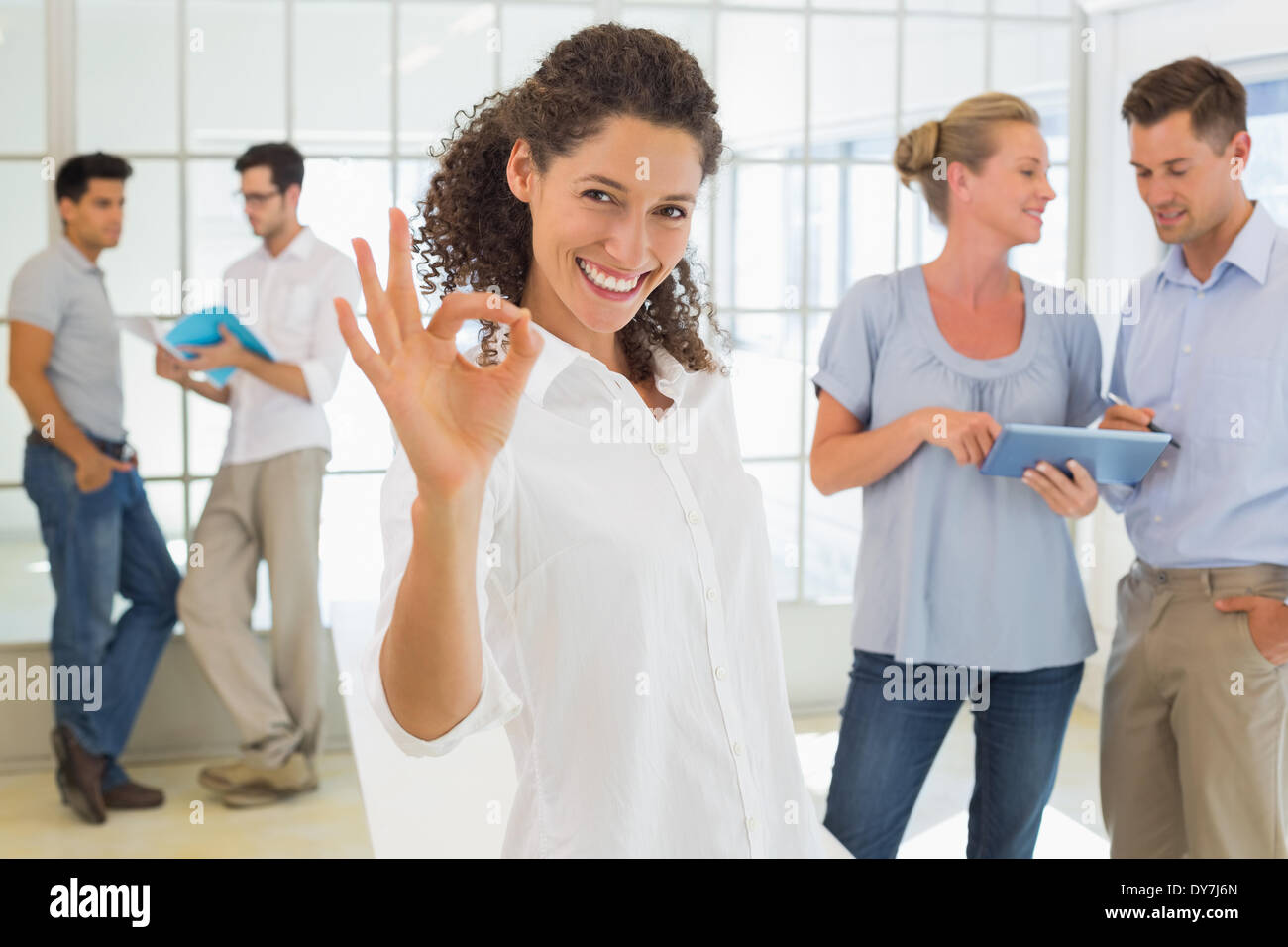 Casual businesswoman giving ok sign to camera Stock Photo - Alamy