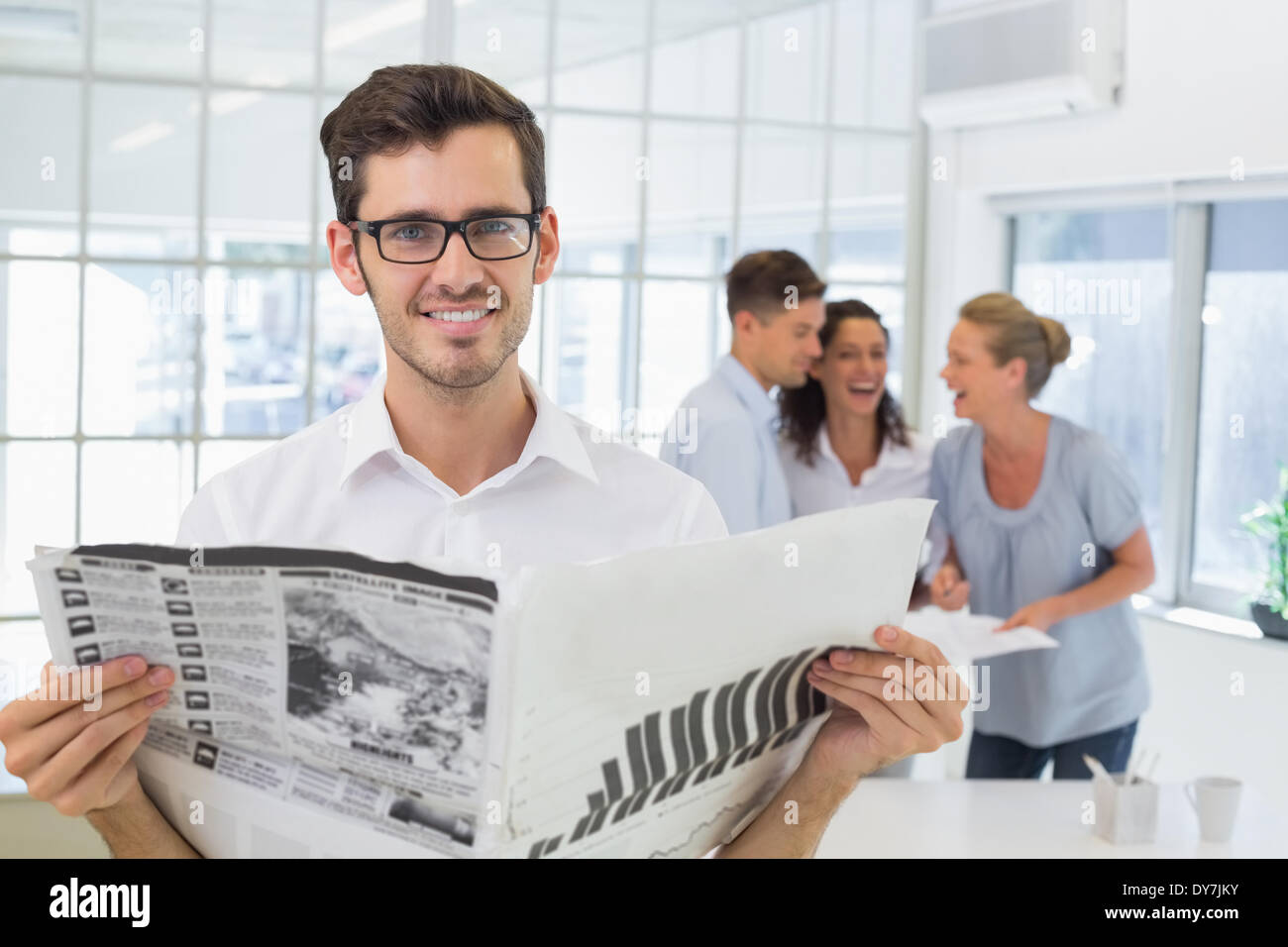 Casual businessman holding newspaper smiling at camera Stock Photo - Alamy