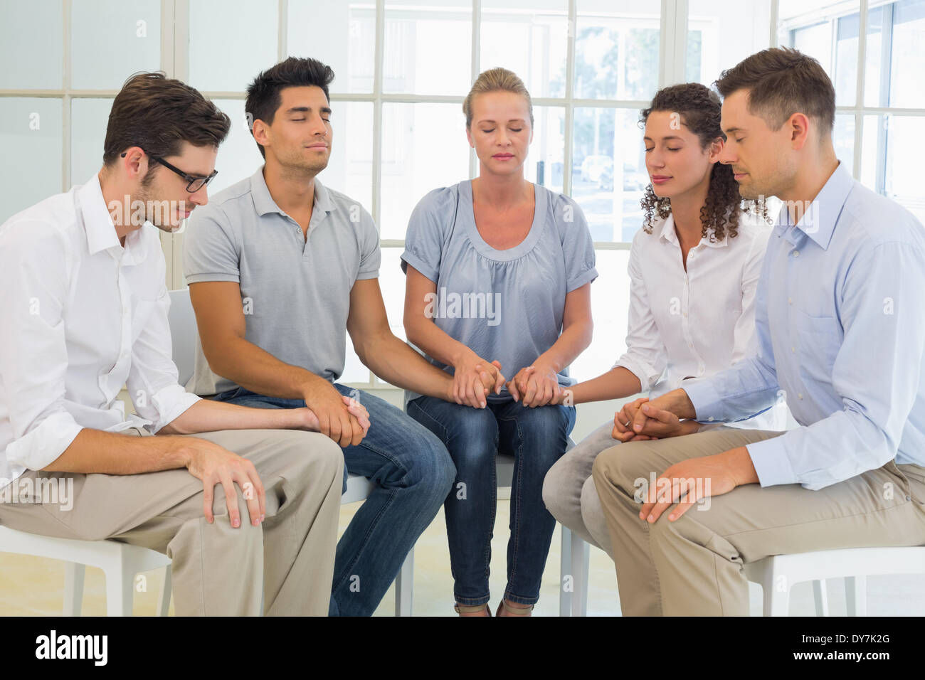 Group therapy in session sitting in a circle holding hands Stock Photo ...