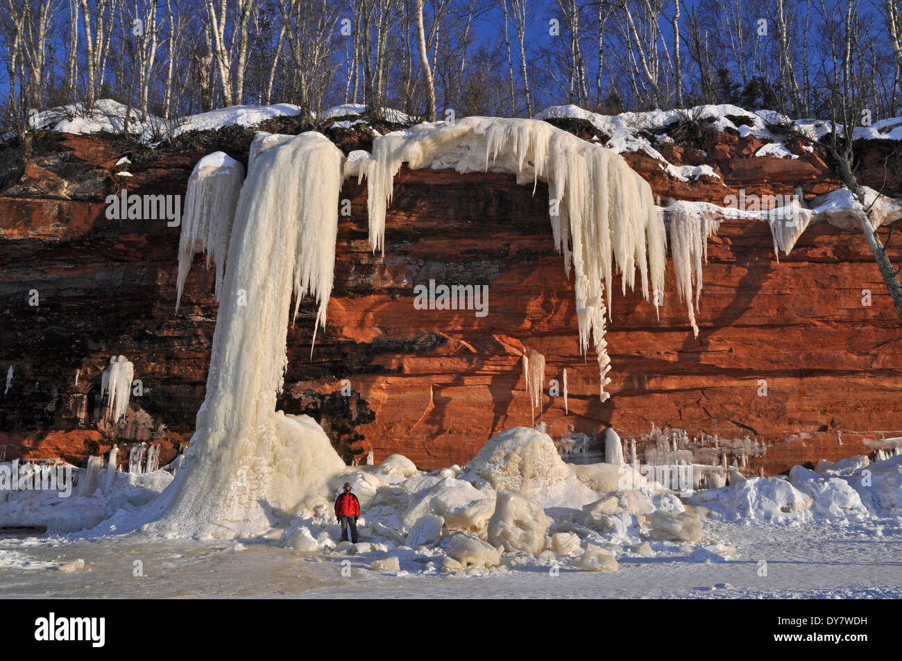 Frozen waterfall, ice chunks and icicles hanging from red sandstone ...