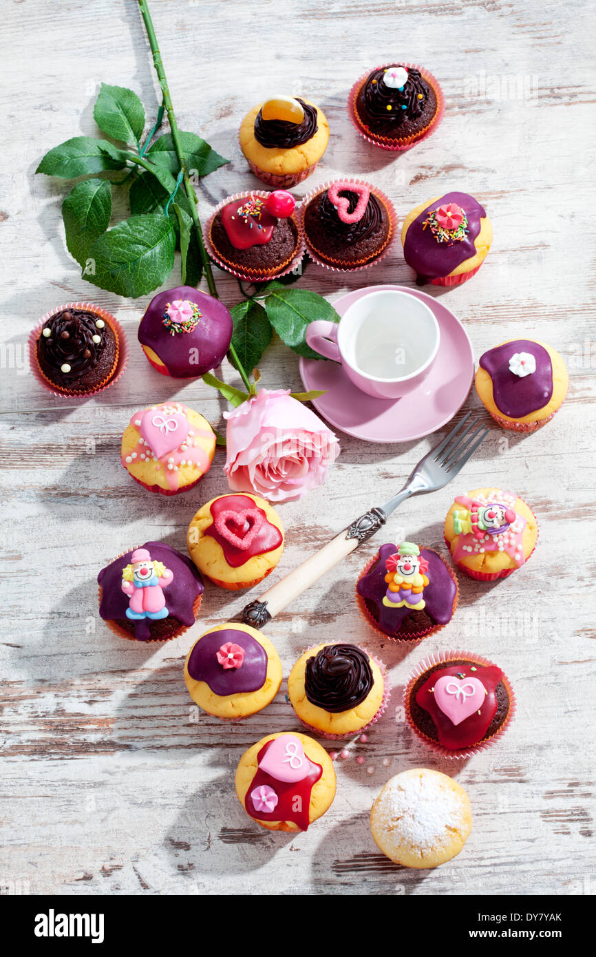 Different decorated muffins in muffin papers, cup, fork and single rose ...