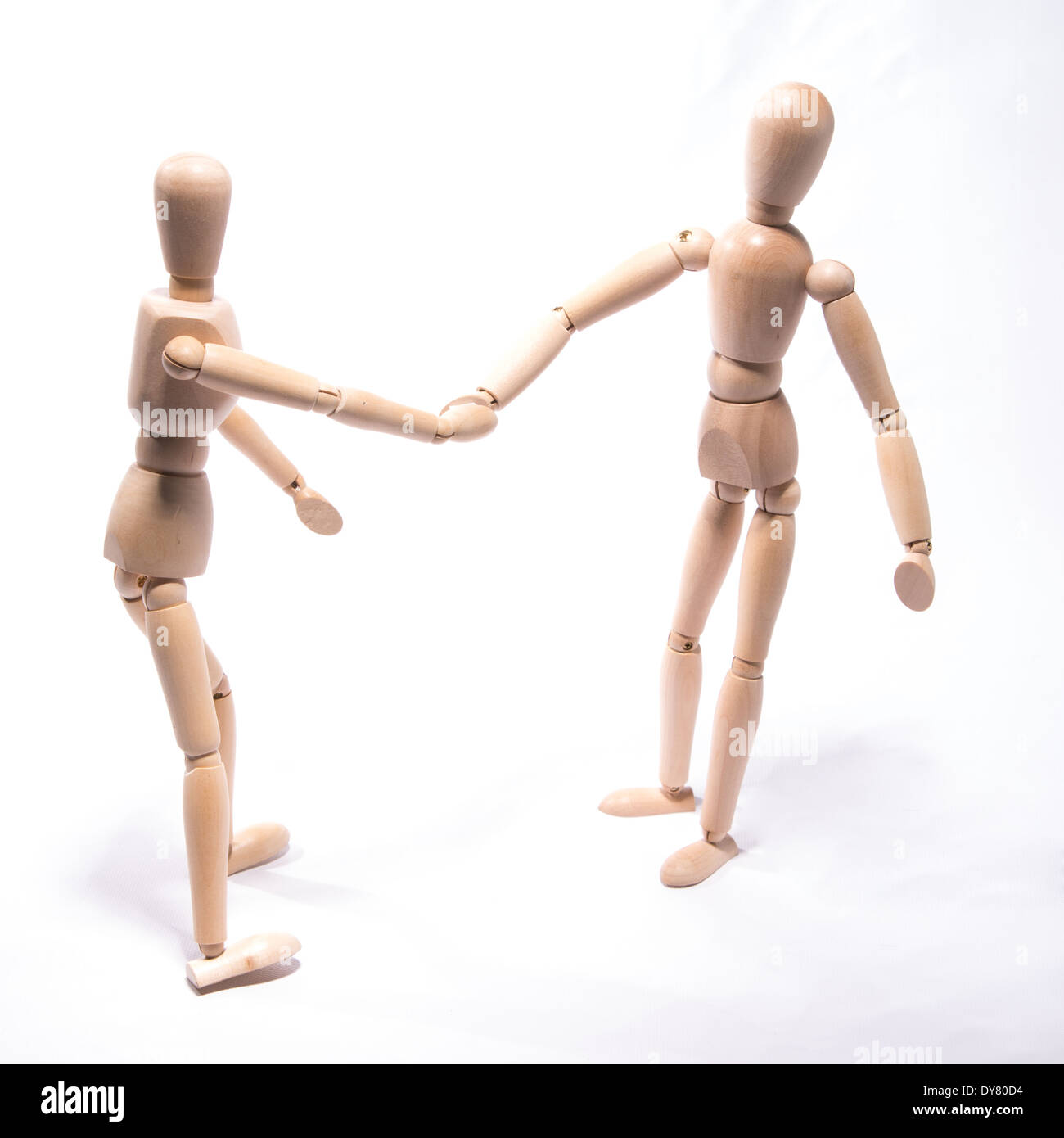 Toy dolls reaching out for handshake Stock Photo - Alamy