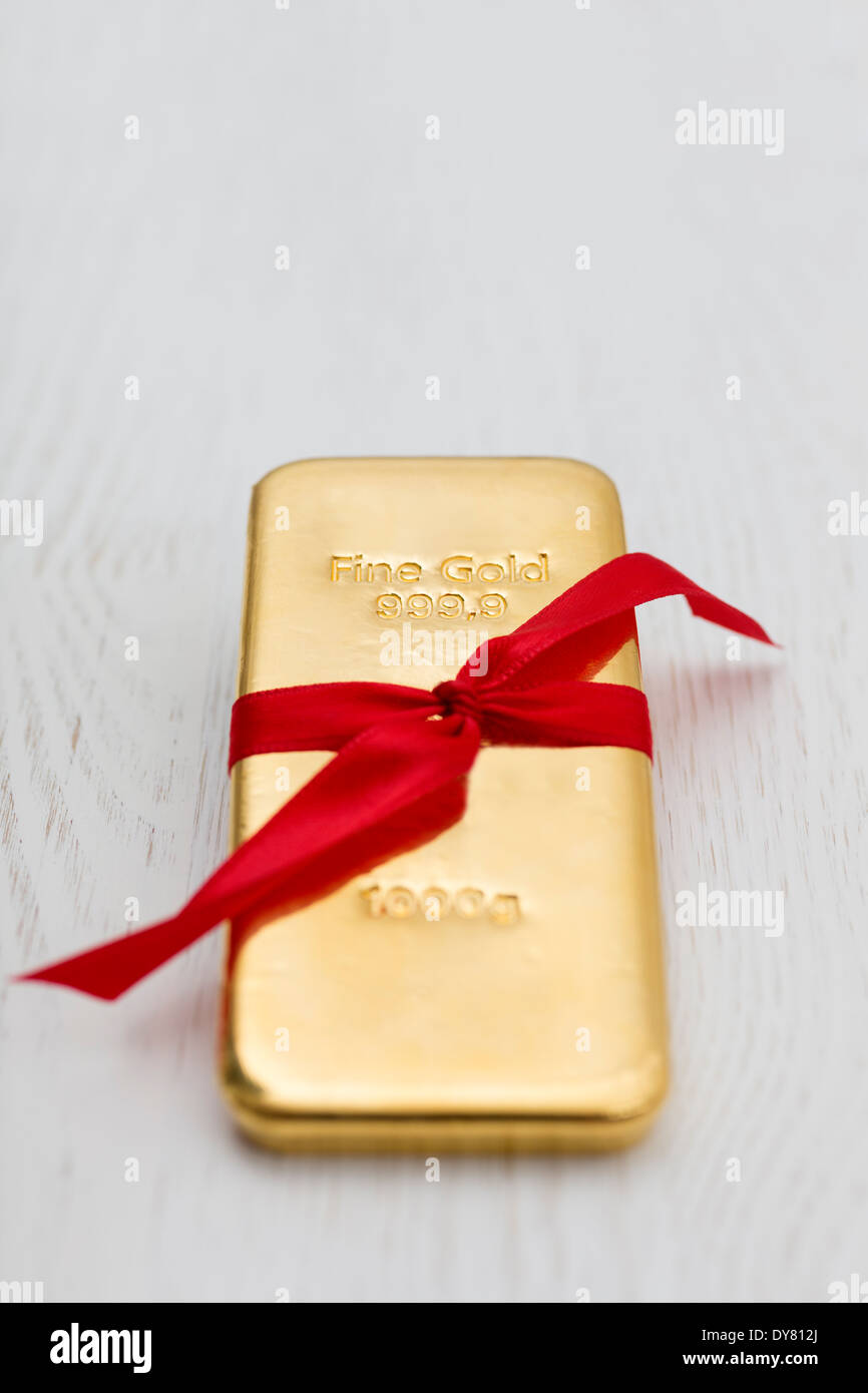 Gold bar with red ribbon Stock Photo - Alamy