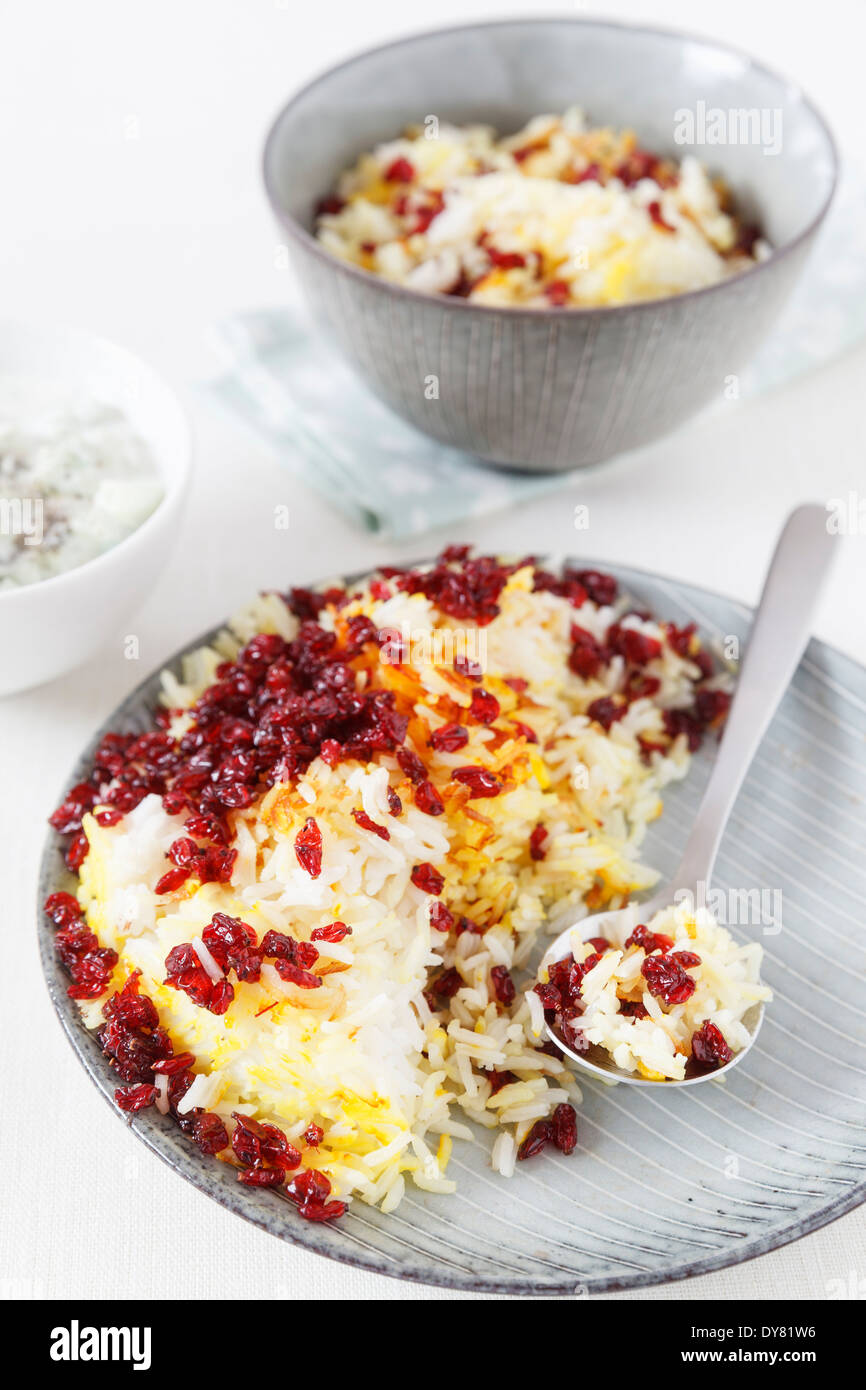 Persian saffron rice with barberries and bowl of mint yoghurt on white ...