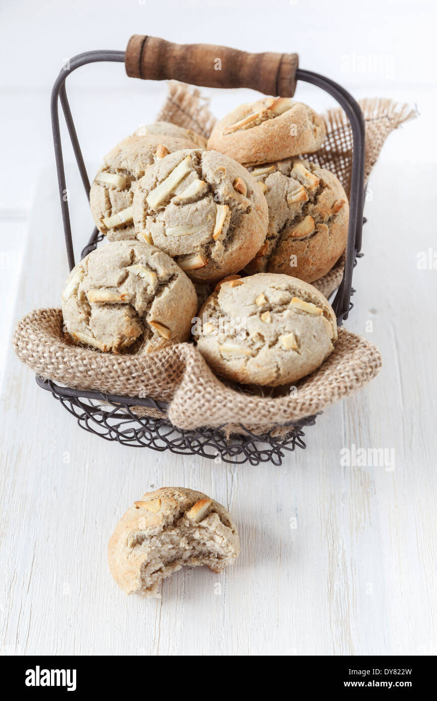 Wire basket of glutenfree garlic buckwheat rolls on white wooden table ...