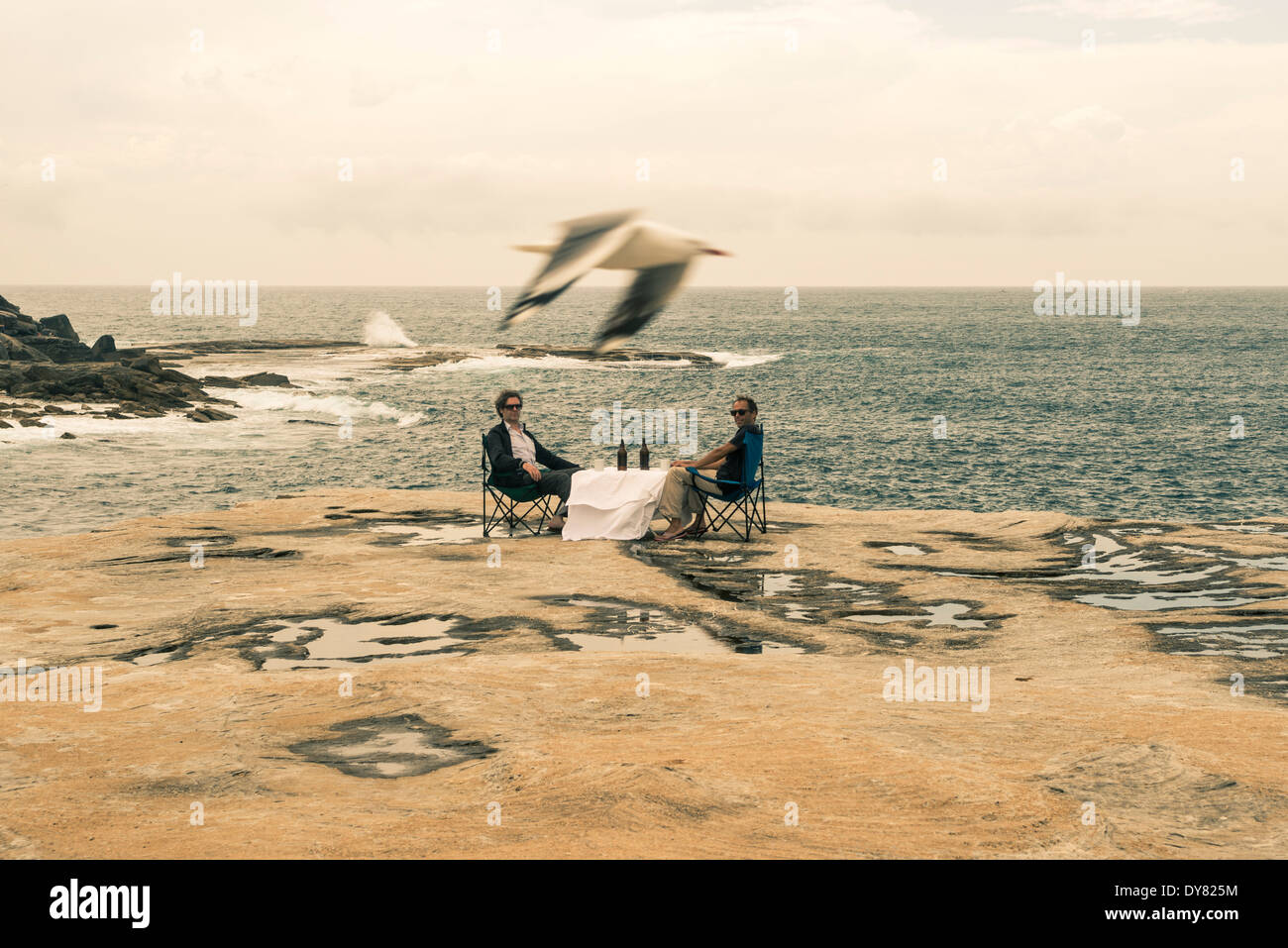 Australia, Sydney, two men sitting with beer at table on cliff Stock ...