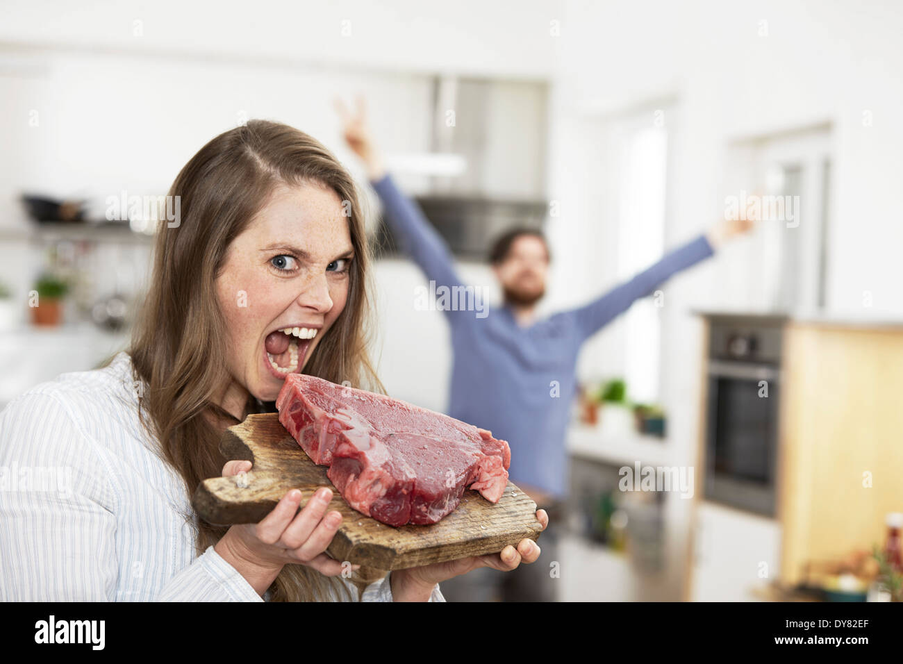 Happy young womanpretending to bite into raw steak Stock Photo - Alamy