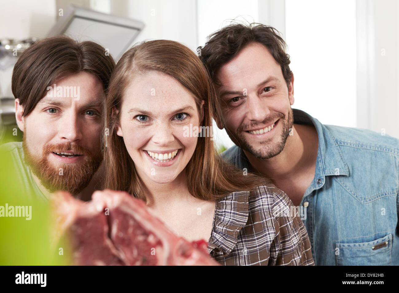 Portrait of three friends in kitchen with steak Stock Photo - Alamy