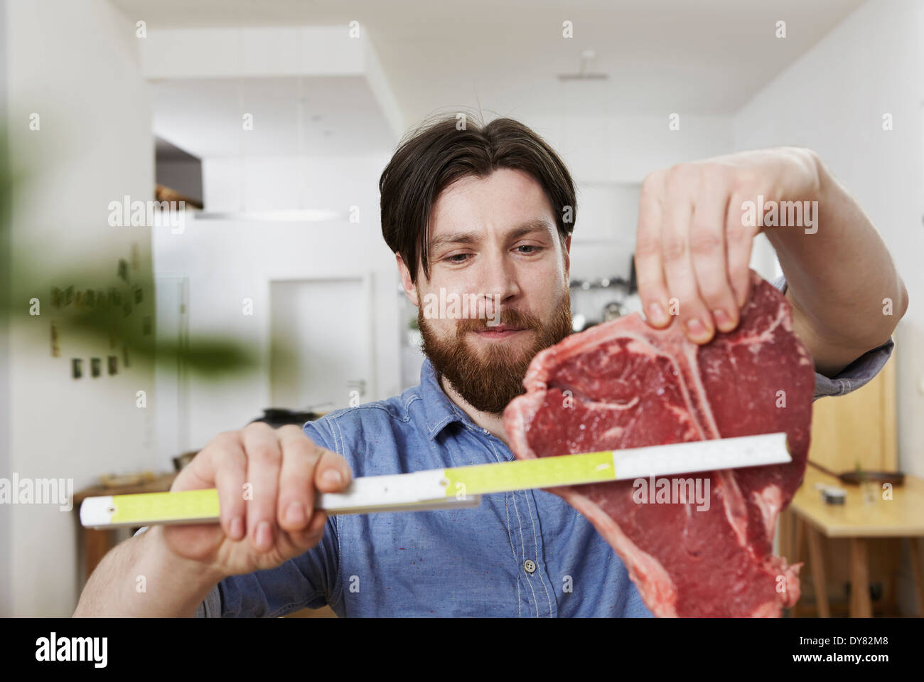 Man in kitchen holding large steak Stock Photo - Alamy