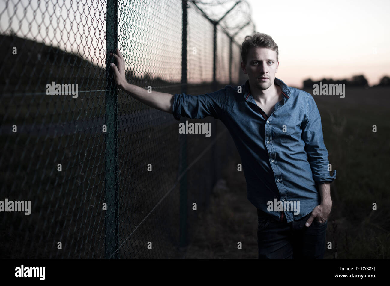 Young man at a chain link fence Stock Photo - Alamy