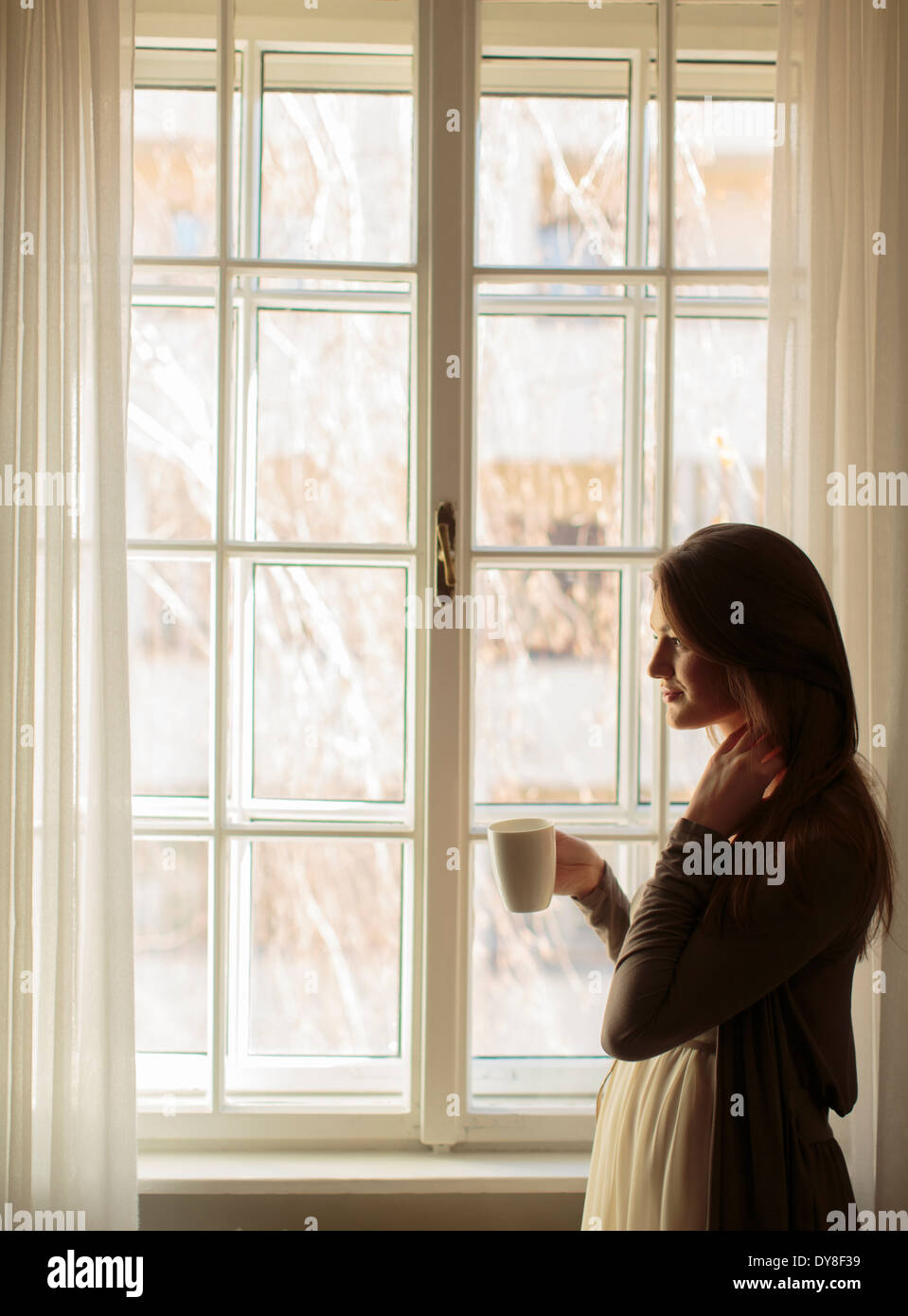 Pretty young woman by the window Stock Photo - Alamy