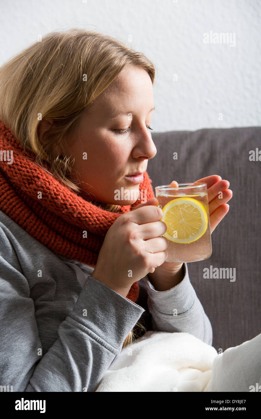 Young woman has a cold, fever, flu, drinking a hot lemon Stock Photo ...