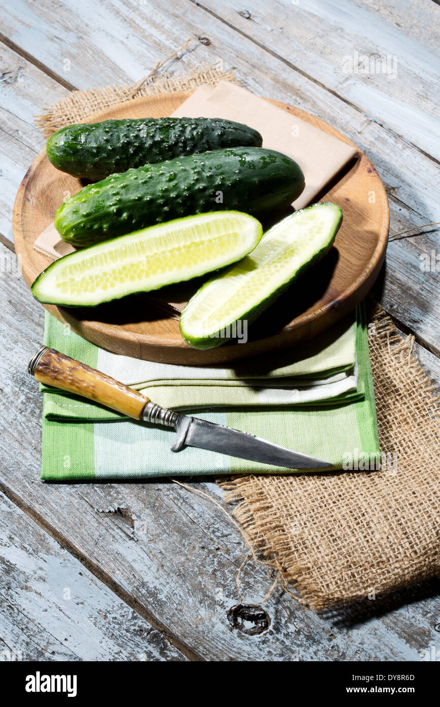 Sliced and whole cucumbers (Cucumis sativus) with knife on chopping ...