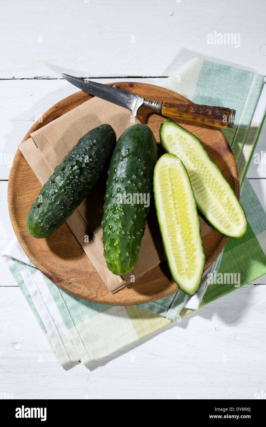 Sliced and whole cucumbers (Cucumis sativus) with knife on chopping ...