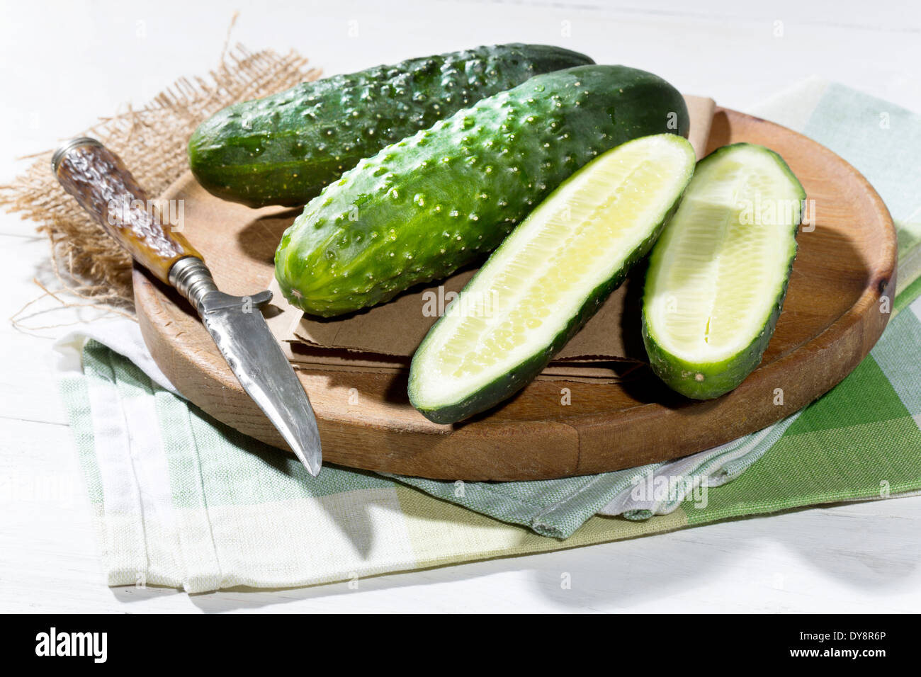 Sliced and whole cucumbers (Cucumis sativus) with knife on chopping ...