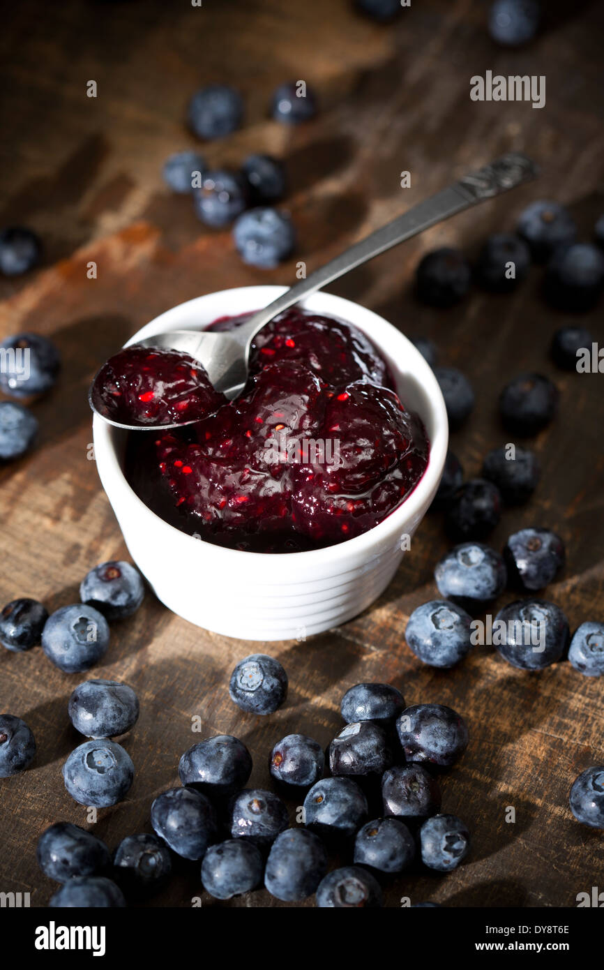 Bowl of blueberry and raspberry jam, spoon and blueberries on dark ...